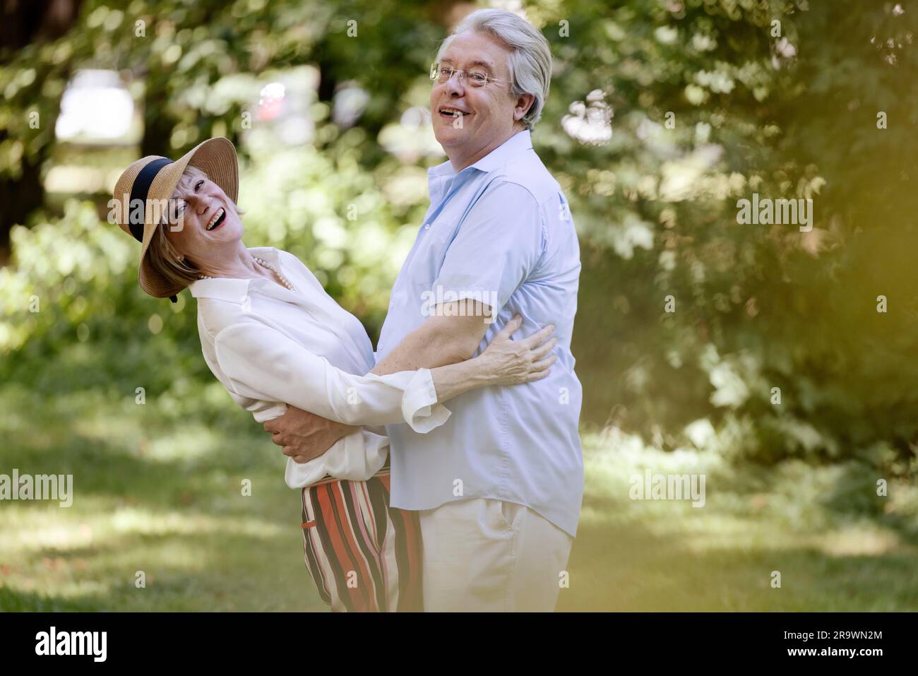 Germany, older couple dressed for summer, hugging and having fun in ...