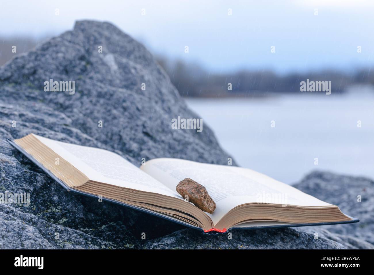 Stone on an open book put on a granite stone under the rain close to ...