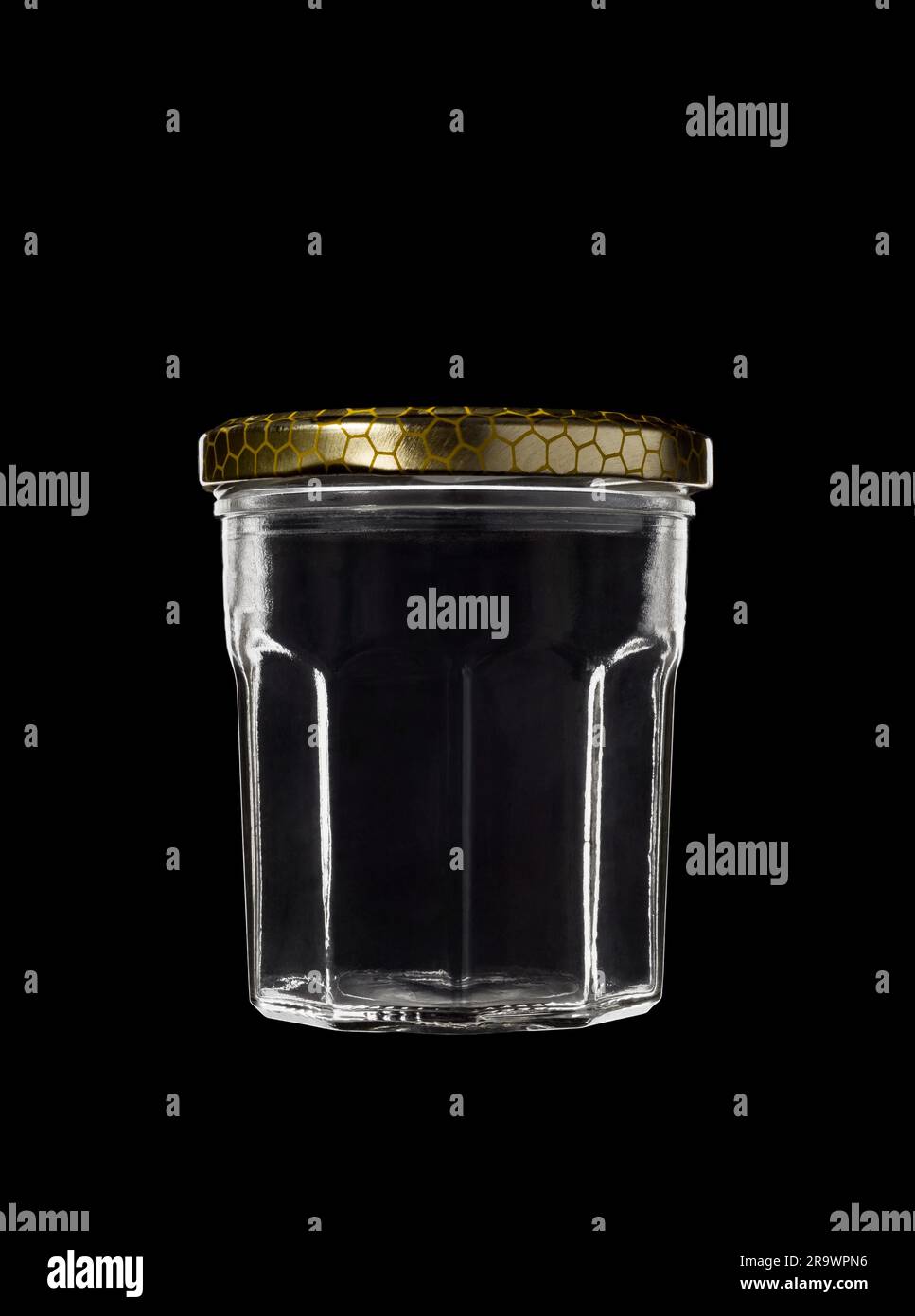 Transparent glass jar on black background, with the closed gold color ...