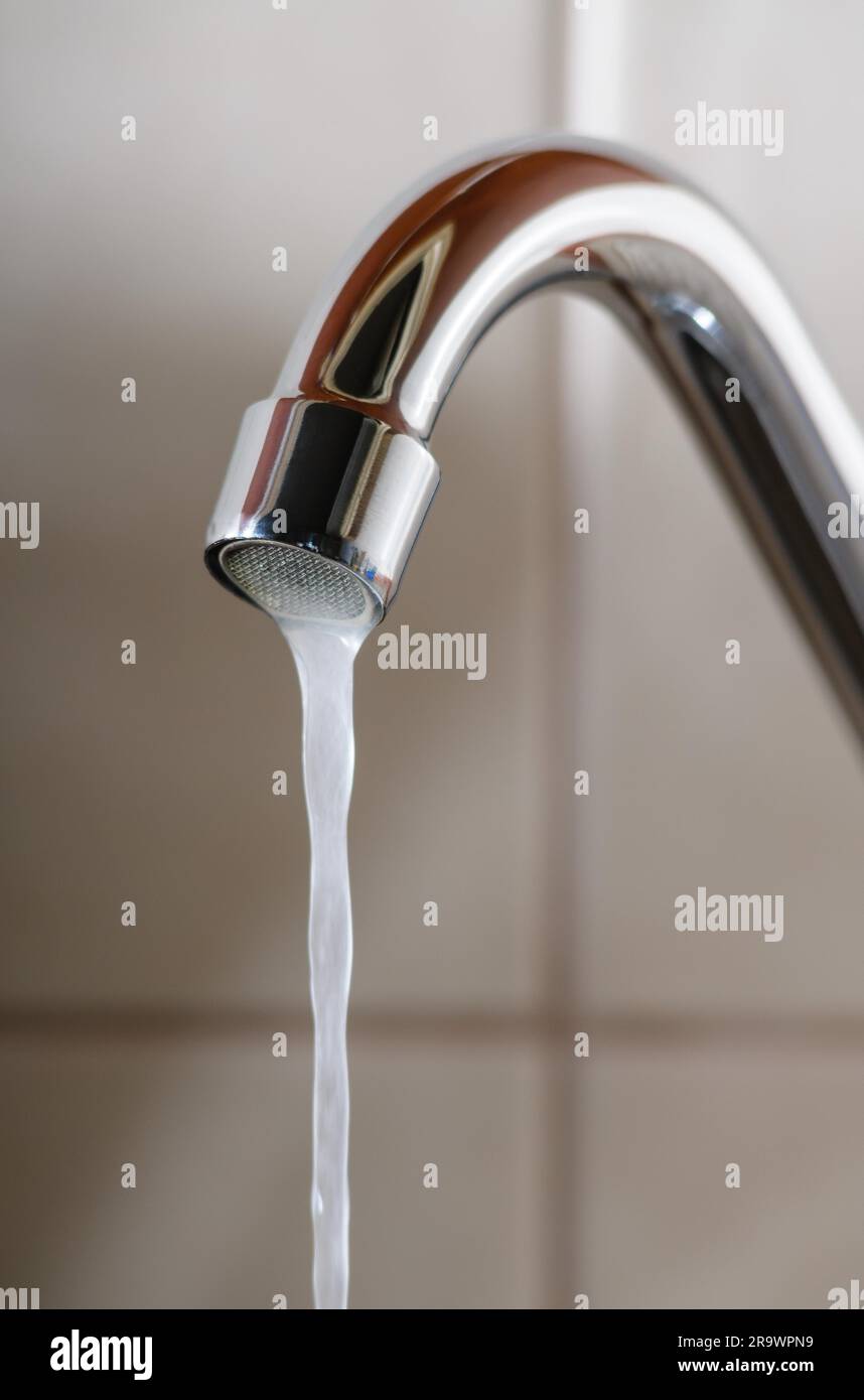 Vertical image of a tap with water flowing slowly during a period of ...