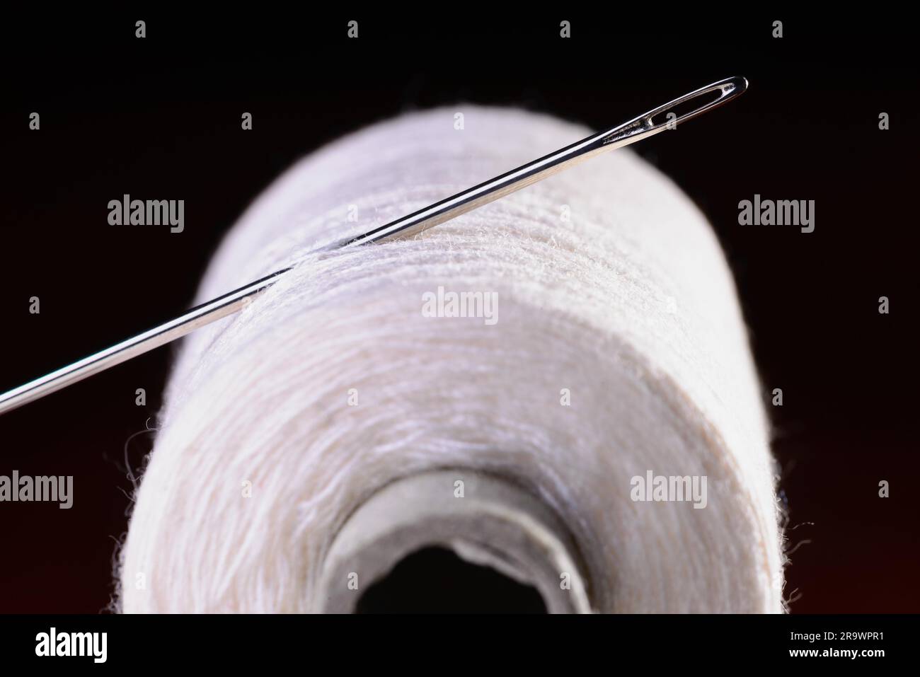 Macro of a white thread roll and needle on black background Stock Photo ...