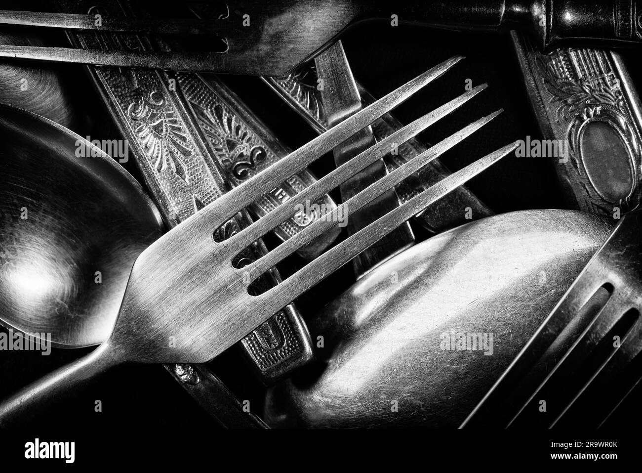 Abstract black and white photo of mixed silver forks, spoons and knives ...