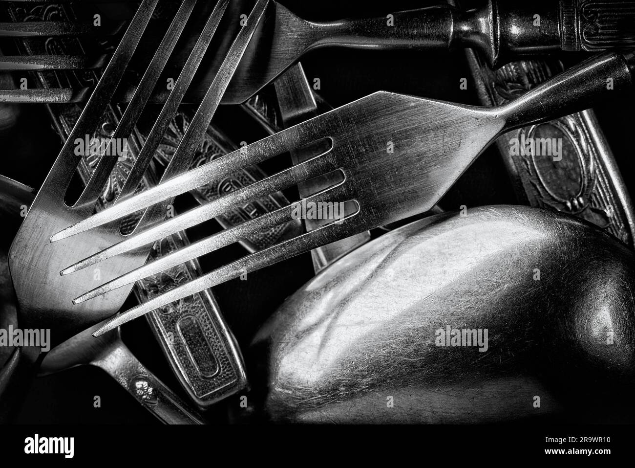 Abstract black and white photo of mixed silver forks, spoons and knives ...