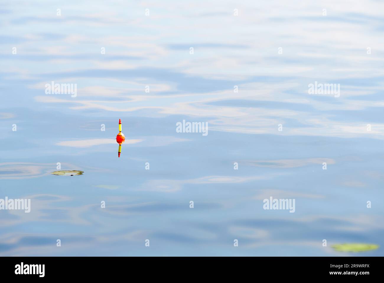 A yellow and orange fishing float in blue water Stock Photo - Alamy