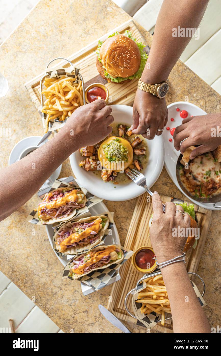 A top view of the hands of people grabbing food from the table served ...