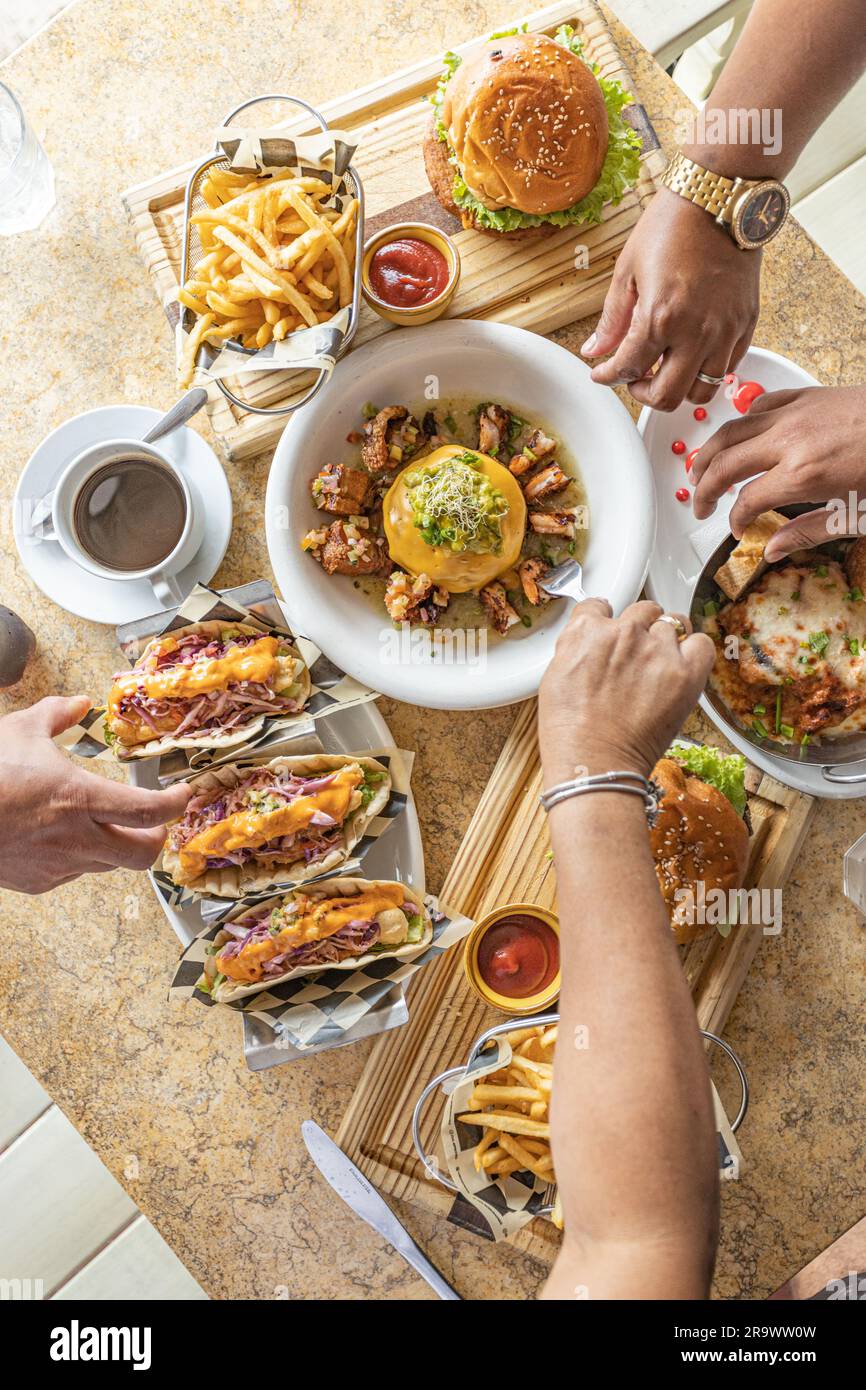 A top view of the hands of people grabbing food from the table served ...