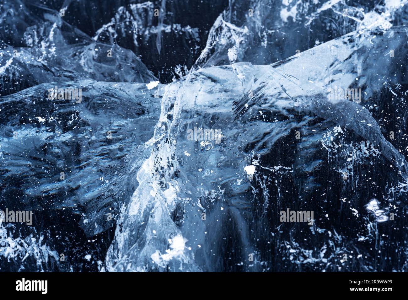 Transparent dark blue ice of frozen Baikal lake with white cracks ...