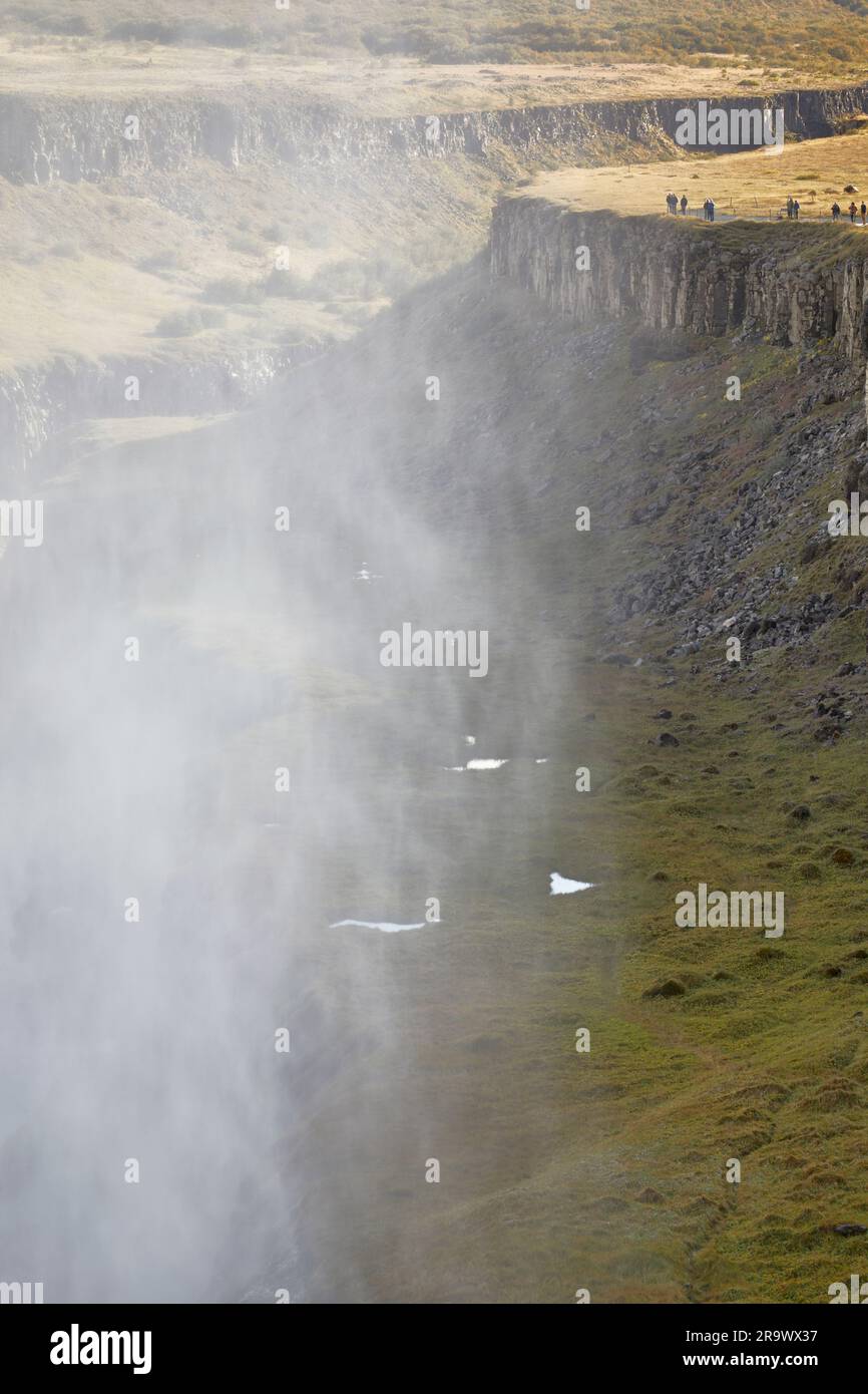Water pours over the final ledge into a chasm creating a cloud of spray ...