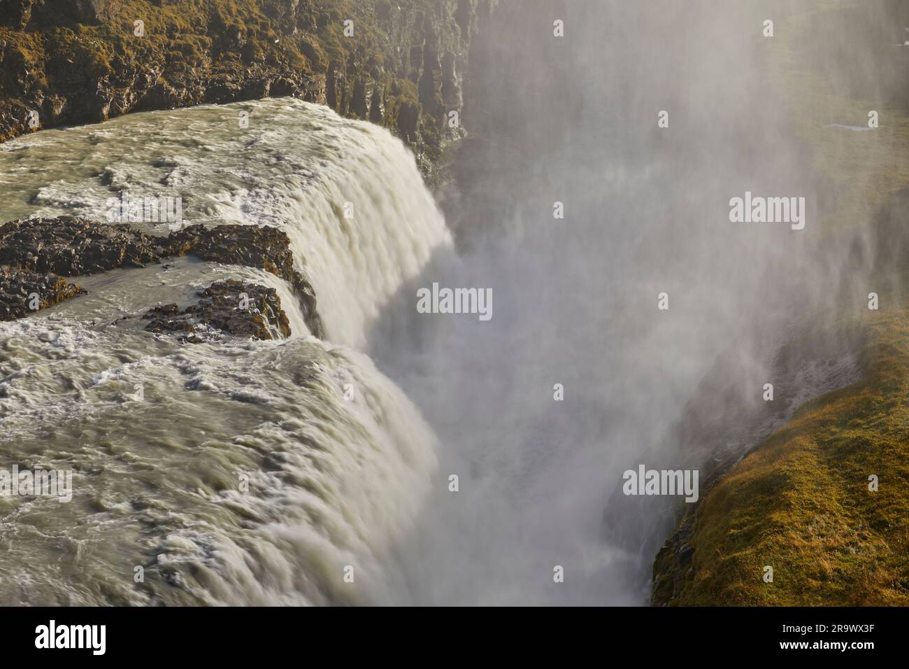 Water pours over the final ledge into a chasm creating a cloud of spray ...