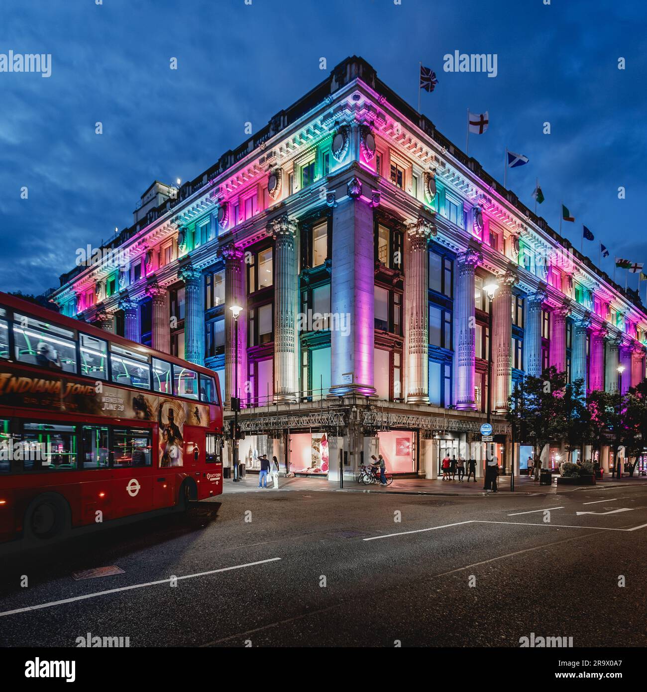 A London red bus outside the facade rainbow illuminated Selfridges ...