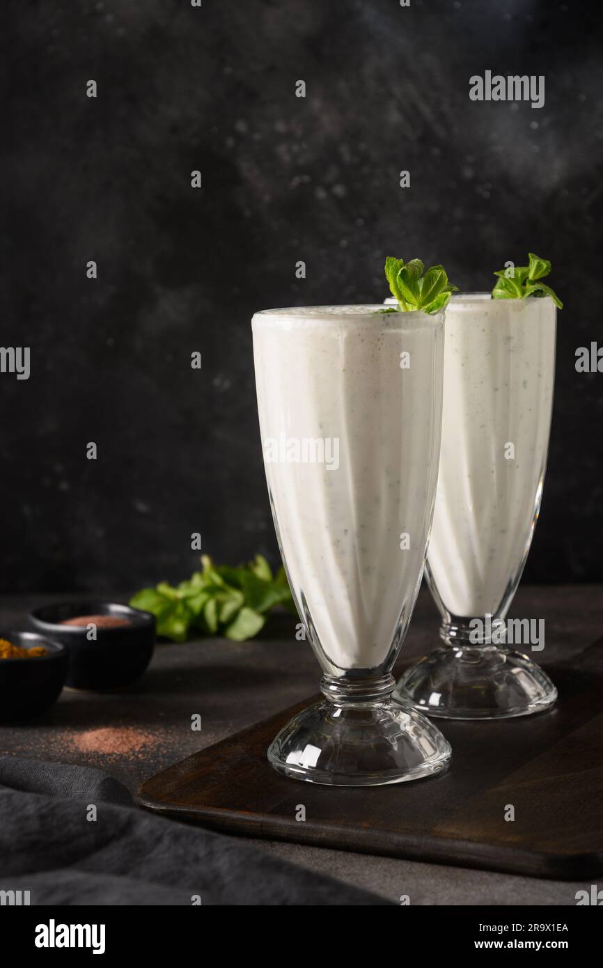 Two Indian Salty lassi with mint leaves and kala namak on black ...