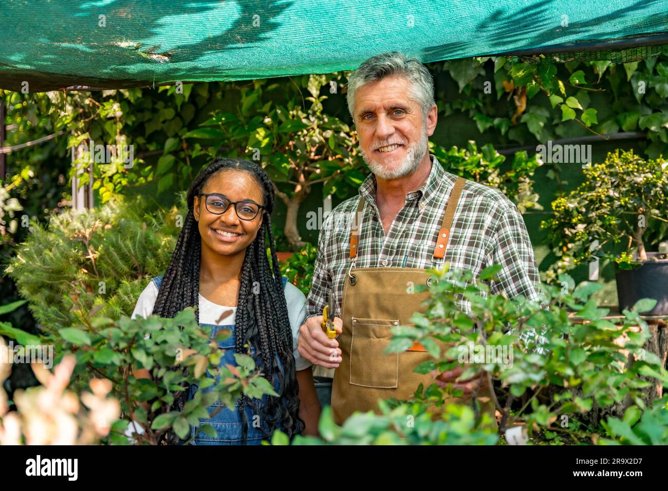 Portrait of master gardener teaching schoolgirl flower nursery in ...