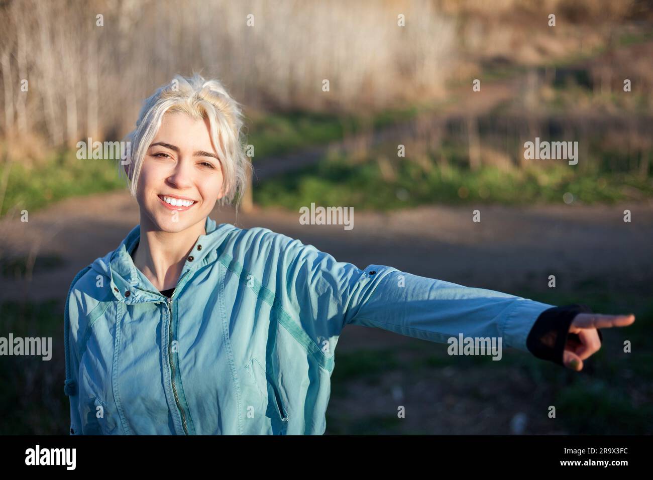 A smiling sporty woman watching and pointing far away Stock Photo - Alamy
