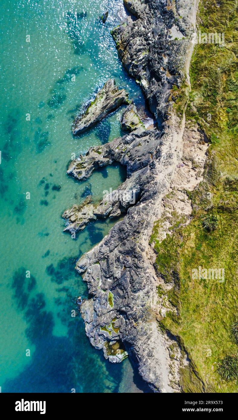 An aerial of a rocky coast of an island with sea water on one side and ...
