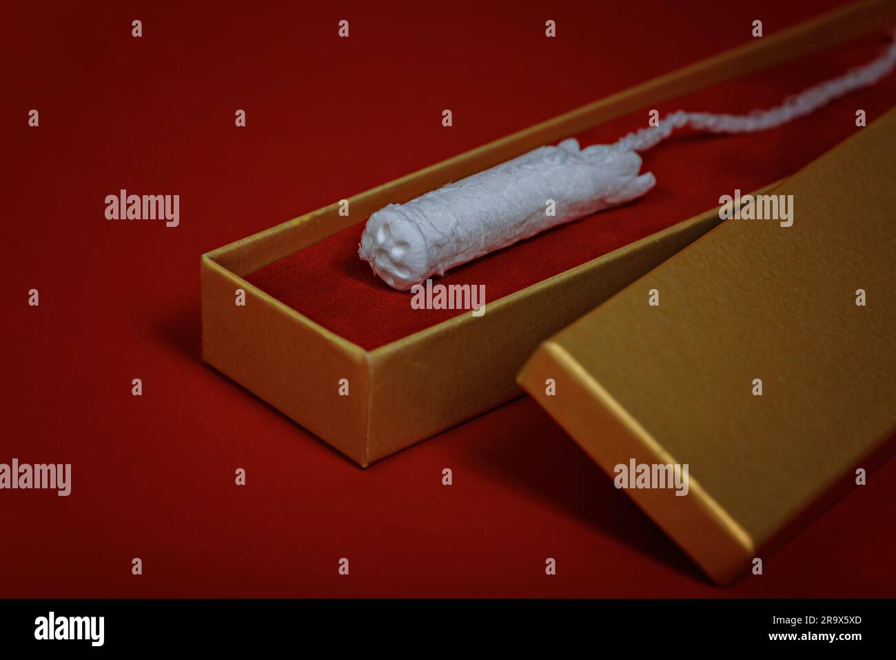 Women's hygienic tampon in a golden gift box on a red background ...