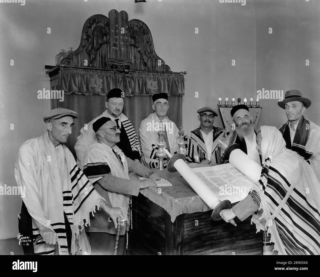 Group of eight men in robes sitting at the altar looking at script ...