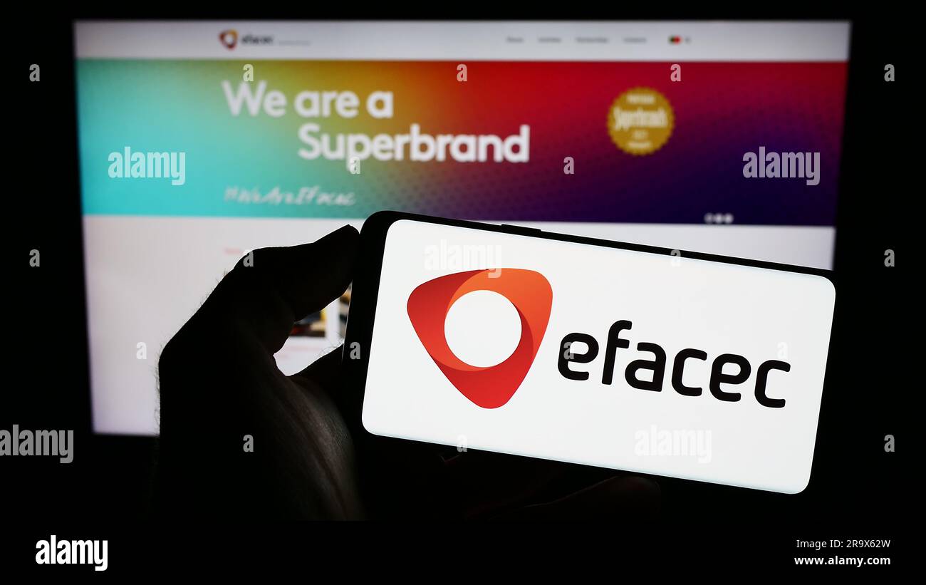 Person holding mobile phone with logo of energy company EFACEC Power ...