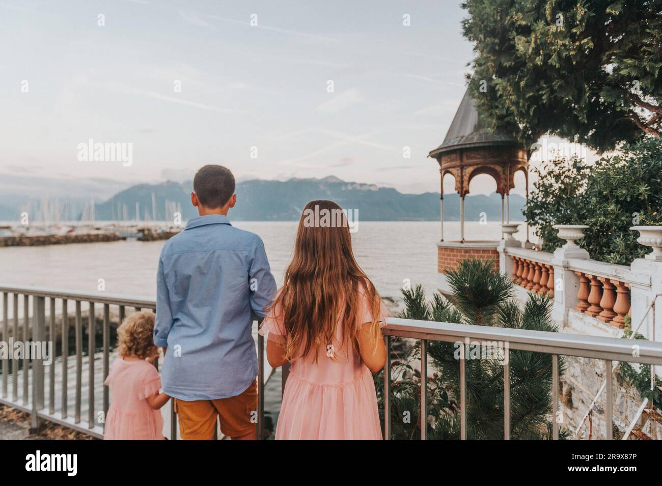 Group of 3 kids admiring sunset over lake Geneva and french Alps ...