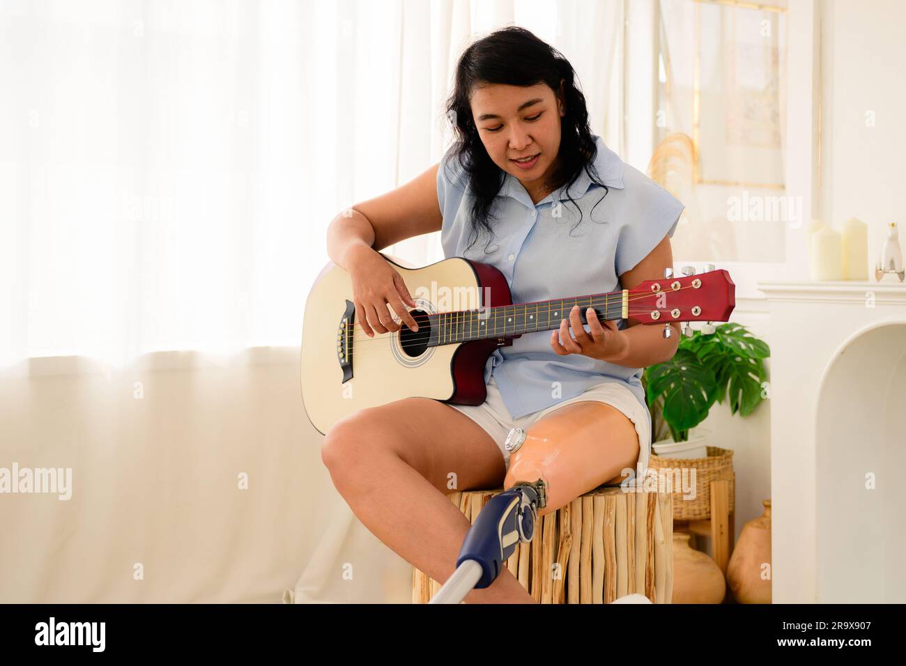 Young woman playing guitar and relaxing at home, Positive woman with ...