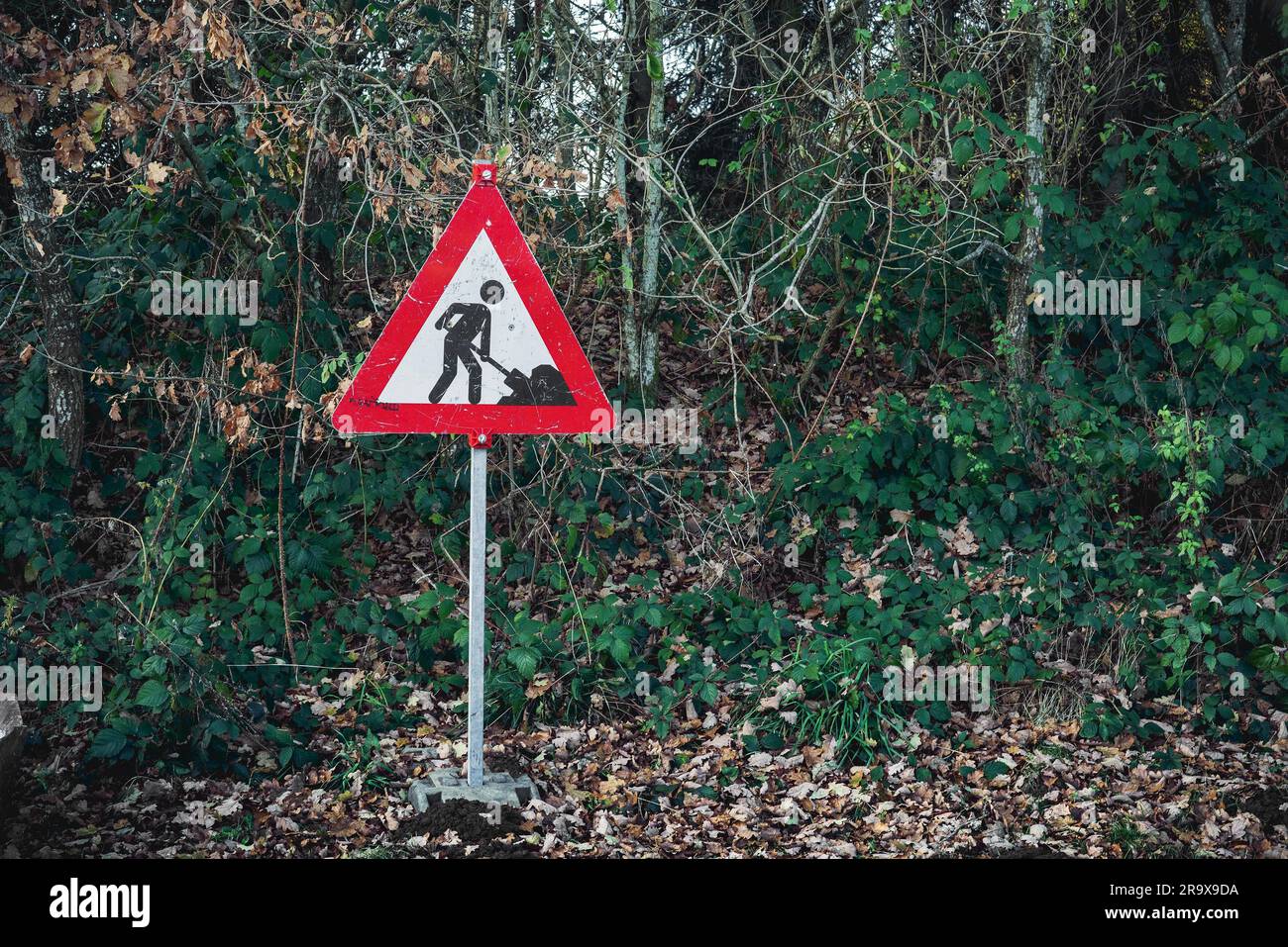 Under construction sign with a digging worker with a shovel on a red ...