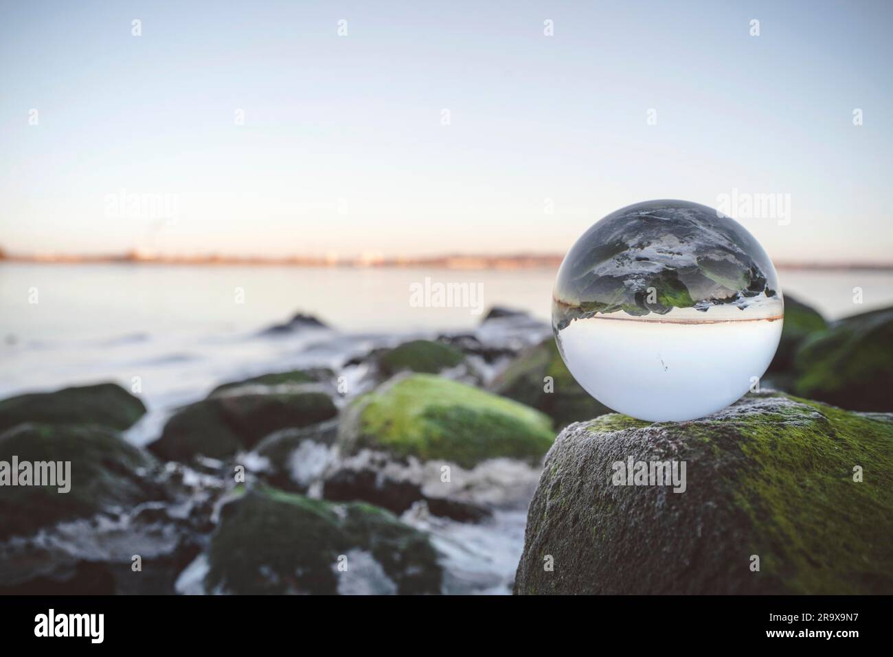 Glass orb on rocks by the sea covered with green moss Stock Photo - Alamy