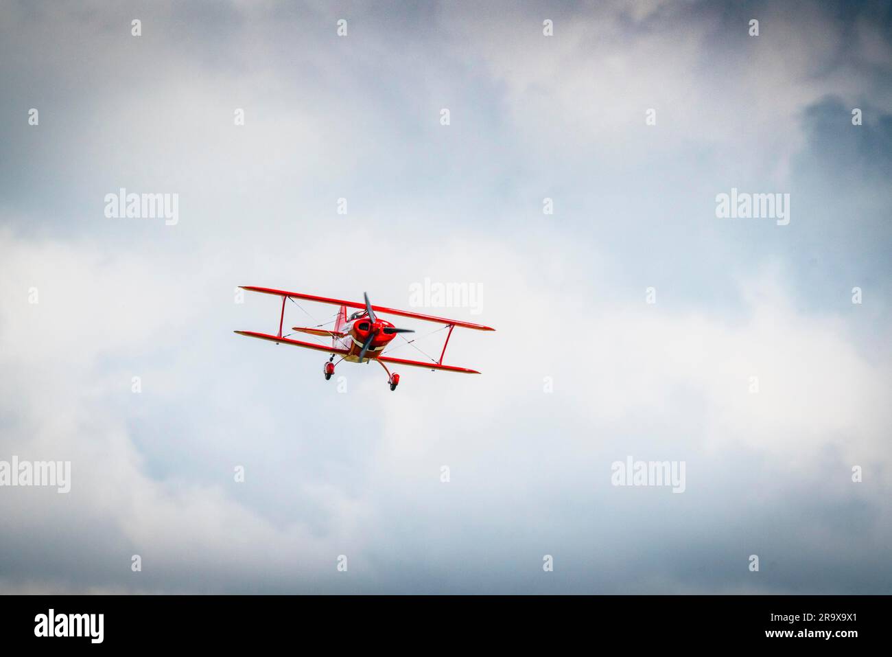 Red propeller airplane flying among the clouds with a storm on the way ...