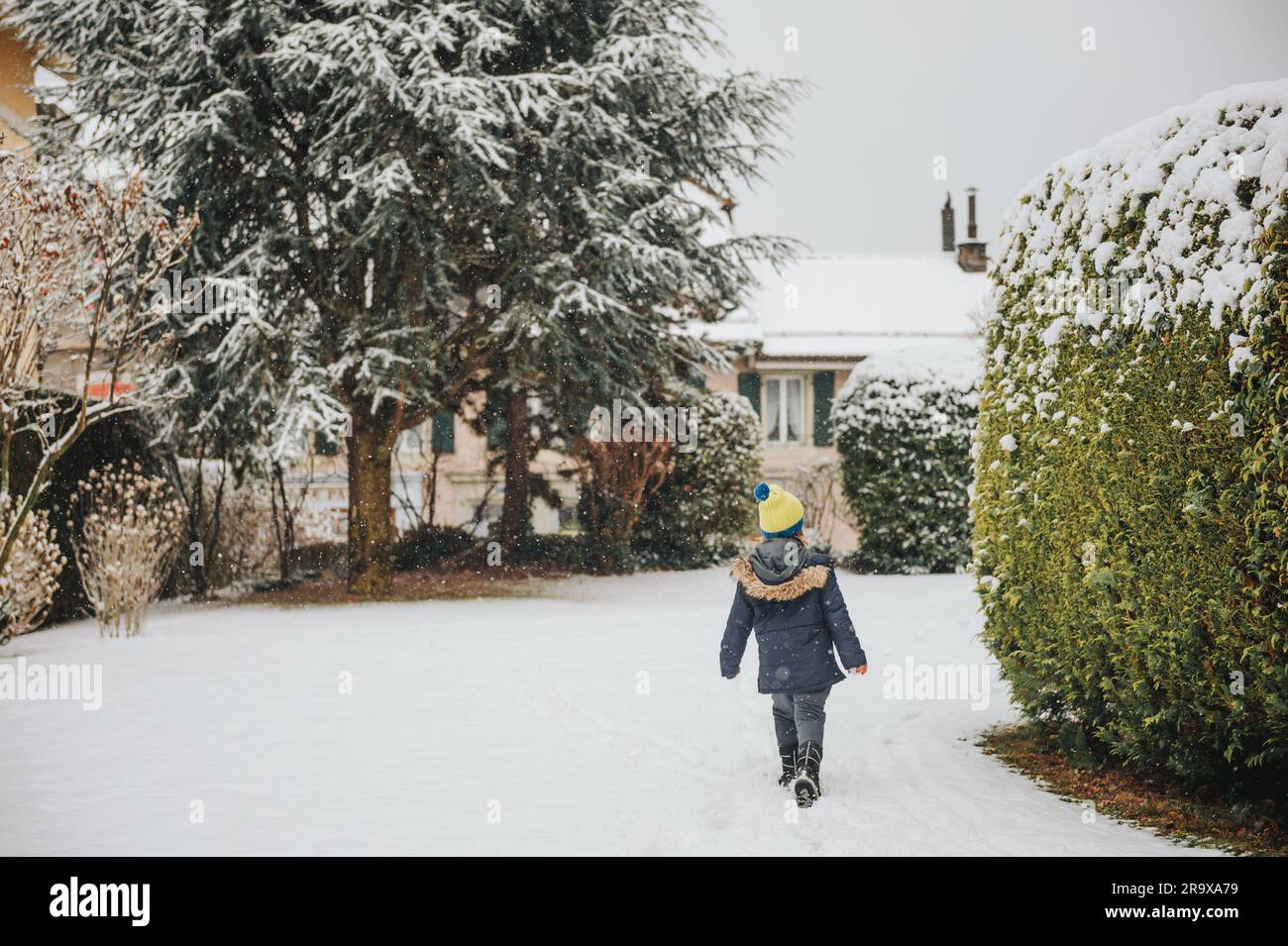 Outdoor portrait of funny little boy having fun under heavy snowfall ...