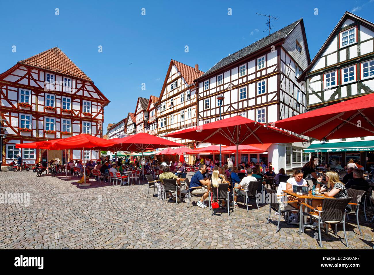 Square with people, outdoor seating under a parasol, half-timbered ...