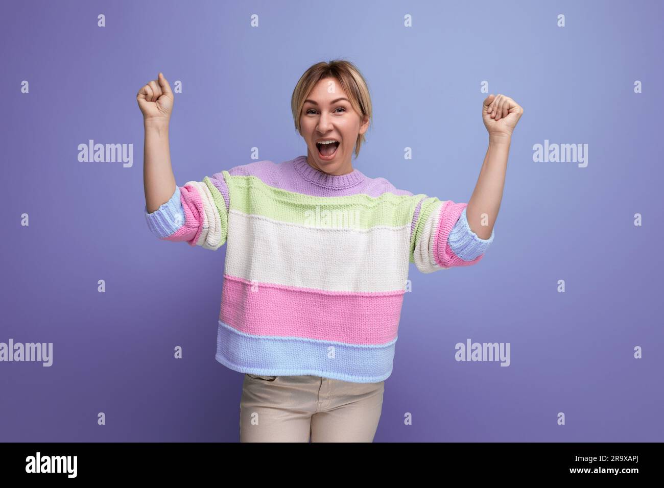 charming blond young woman shouting joyfully from victory holding her ...