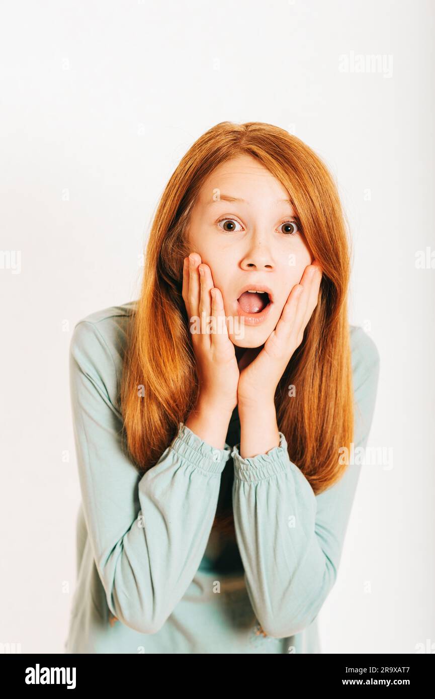 Studio shot of young girl with surprised facial expression, holding ...