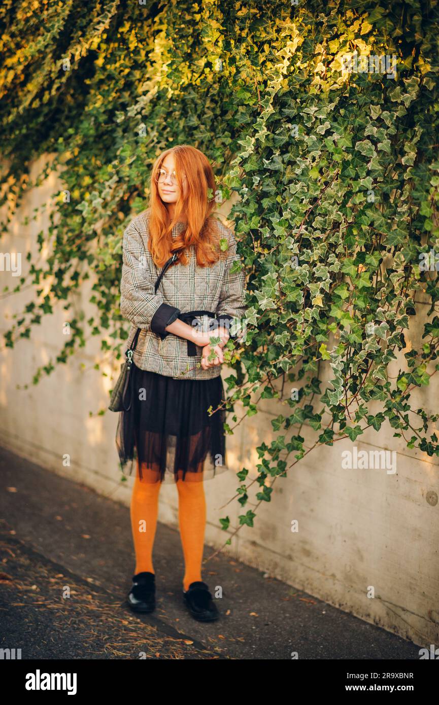 Portrait of adorable little red-haired girl, posing outside, wearing ...