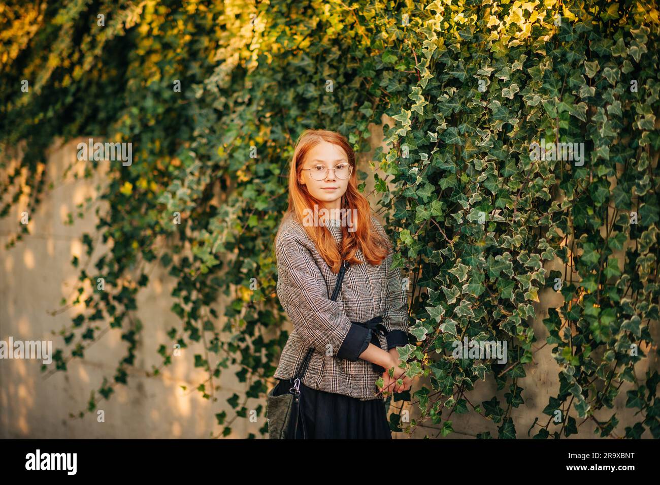 Portrait of adorable little red-haired girl, posing outside, wearing ...