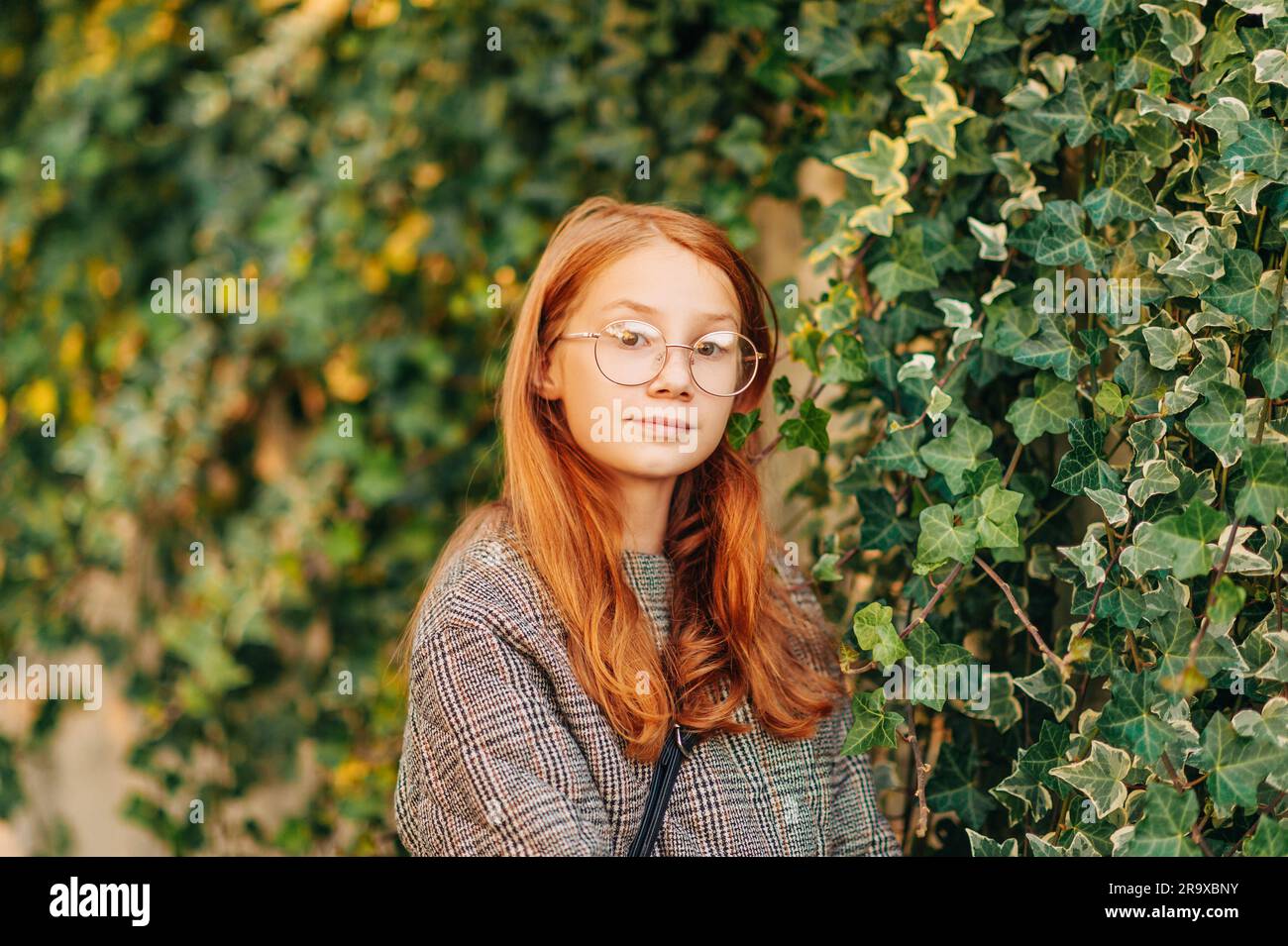 Portrait of adorable little red-haired girl, posing outside, wearing ...