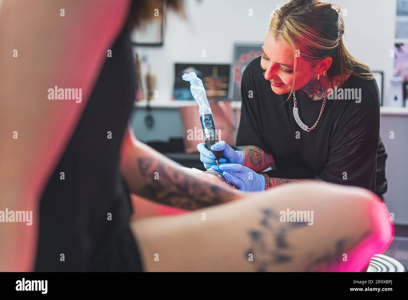 tattoo artist girl drawing a new tattoo and talking to her client ...