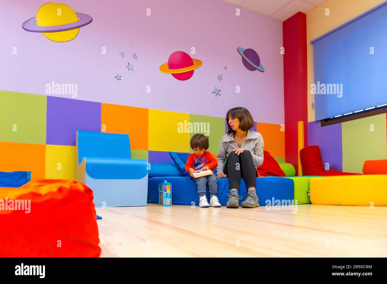 Woman teacher playing with a child sitting reading a book, indoor of a ...