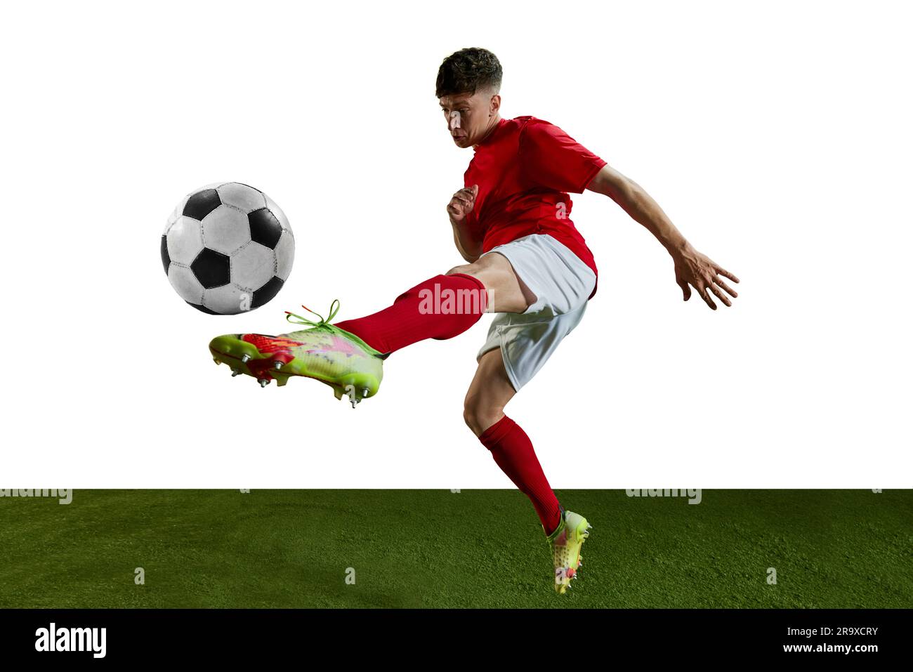 Competitive man, football player in red uniform training, kicking ball ...