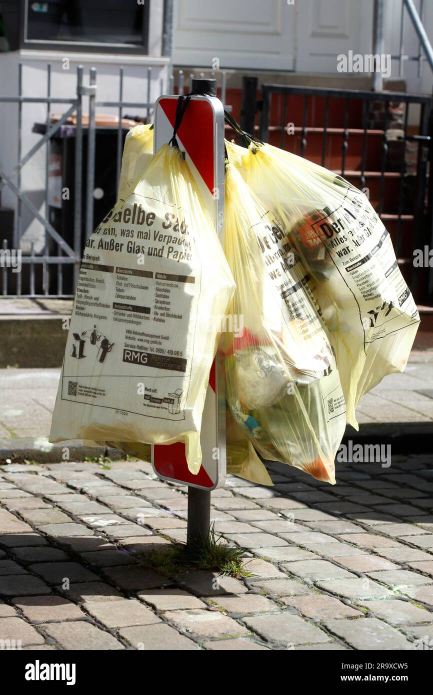 Yellow bags for plastic waste, hanging on a barrier on the street ...