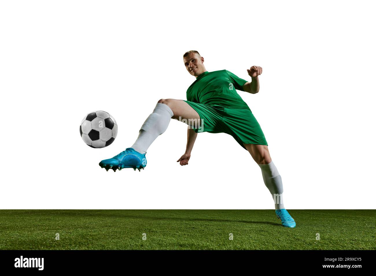 Bottom view. Competitive man, football player in green uniform kicking ...