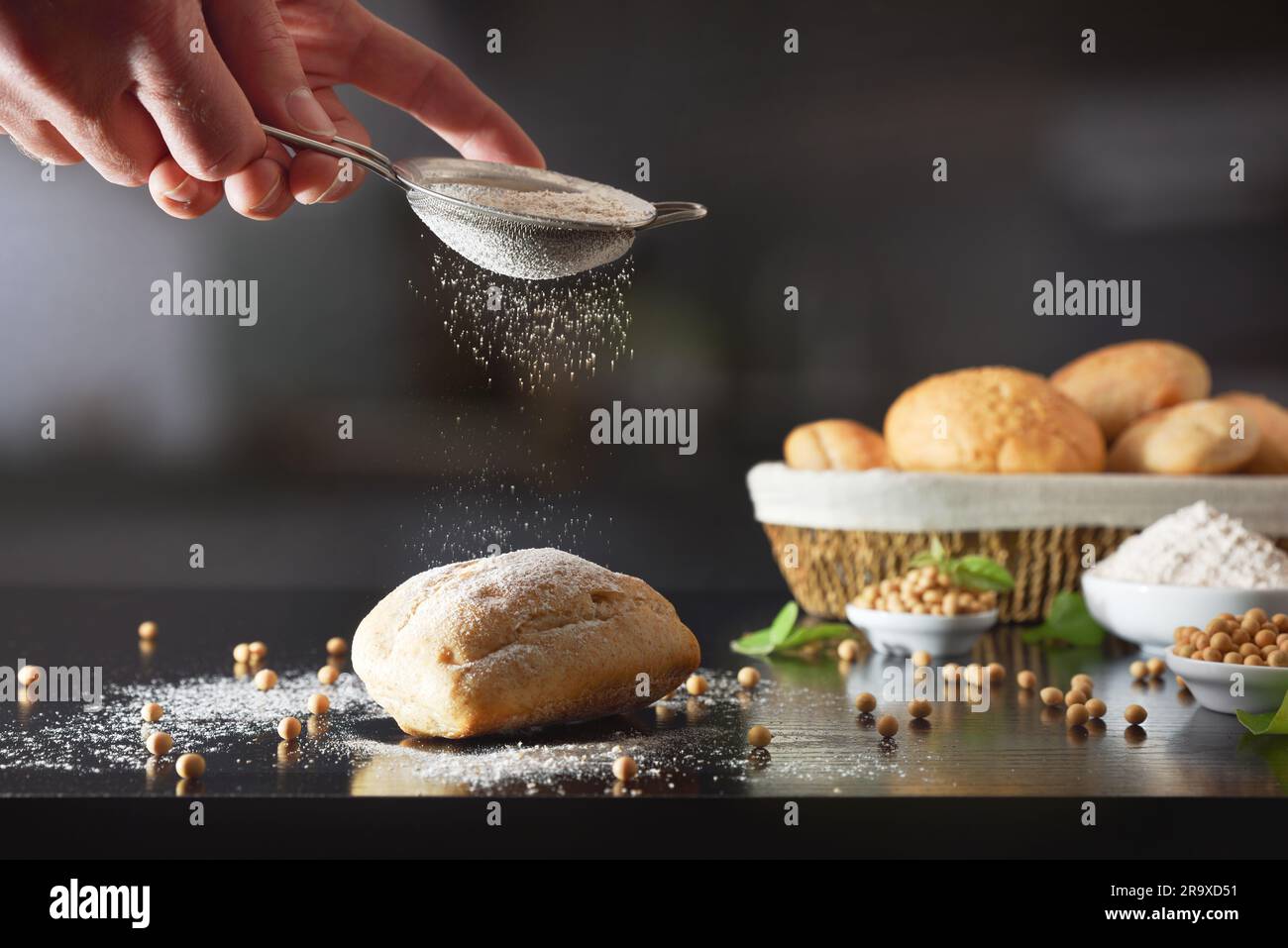 Decorating buns with freshly prepared soy flour on black kitchen bench ...
