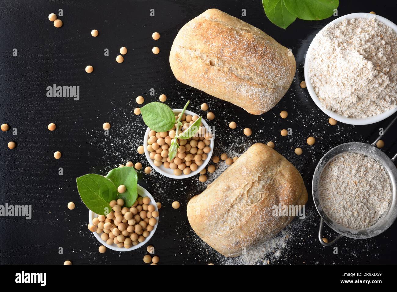 Bread rolls with soy flour on black kitchen bench with bowls full of ...