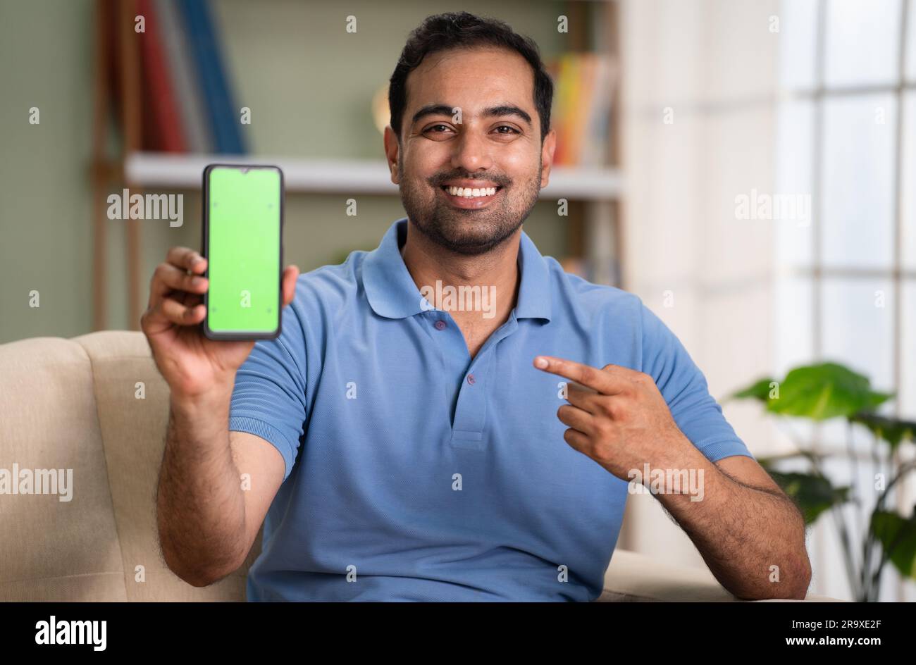 Happy smiling indian man showing green screen mobile phone by pointing ...