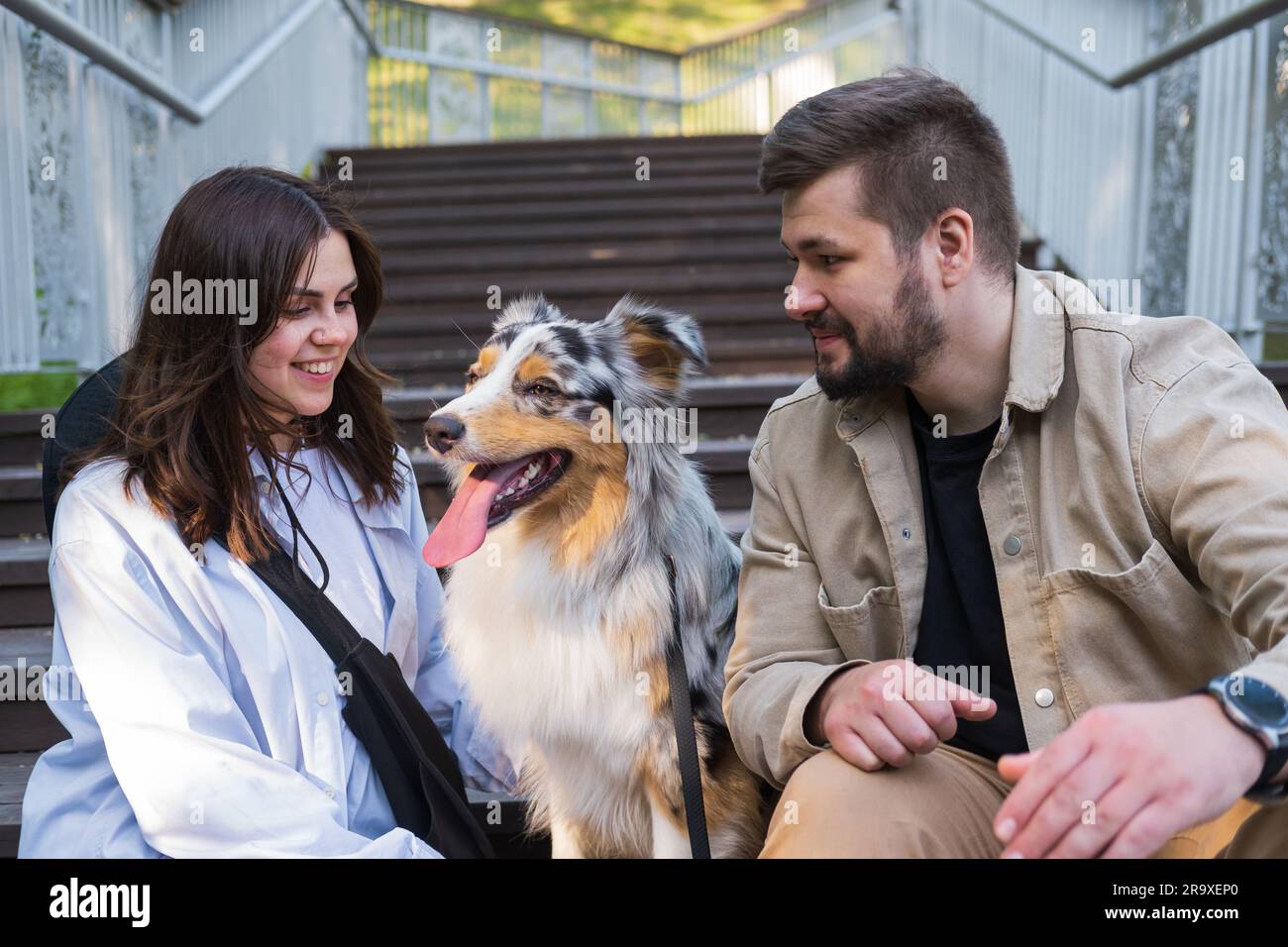 Happy young couple with their aussie shepherd dog outdoors. Young man ...