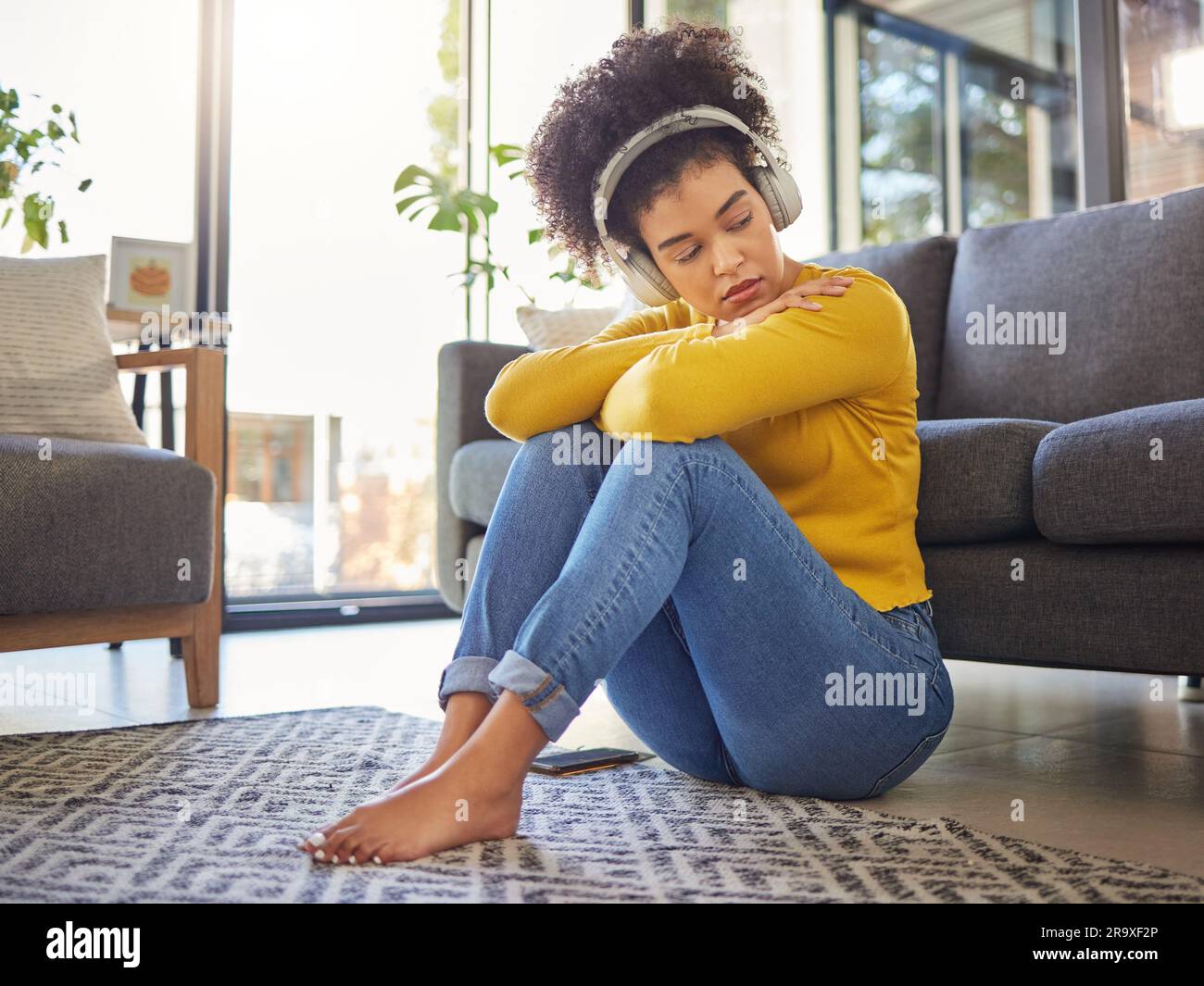 African woman, sad and headphones on floor with worry, stress or memory ...