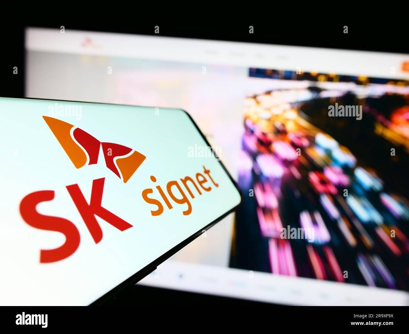 Mobile phone with logo of Korean EV charging company SK Signet on screen in front of business ...