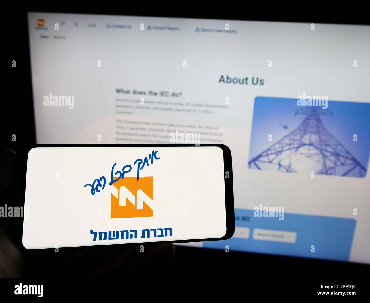 Person holding mobile phone with logo of utility company Israel ...