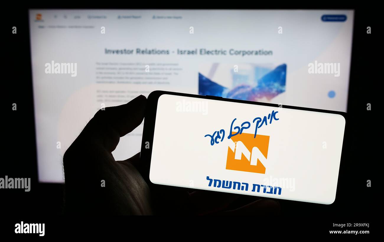 Person holding cellphone with logo of utility company Israel Electric ...
