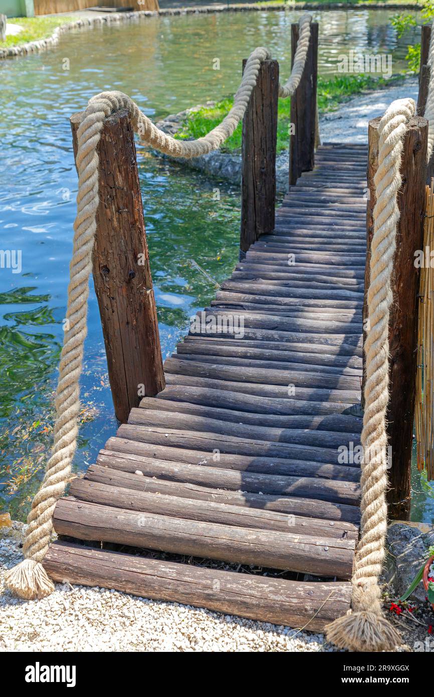Wooden Log Bridge With Rope Over Small Pond Stock Photo - Alamy