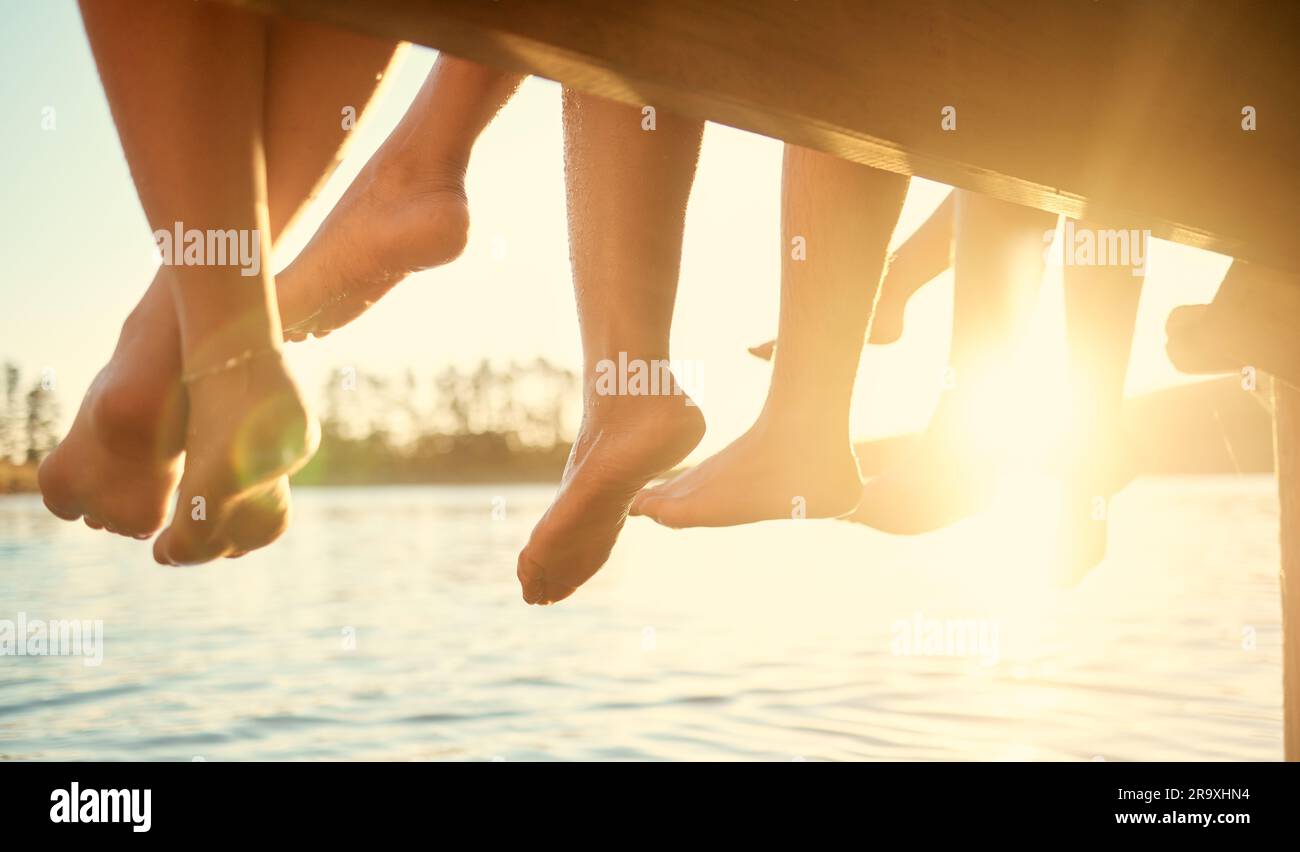 Group, feet on water and friends together at ocean, pier or outdoor in ...
