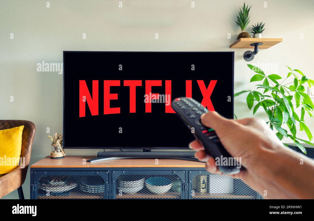 Hand of a black woman holding a remote control and watching Netflix ...