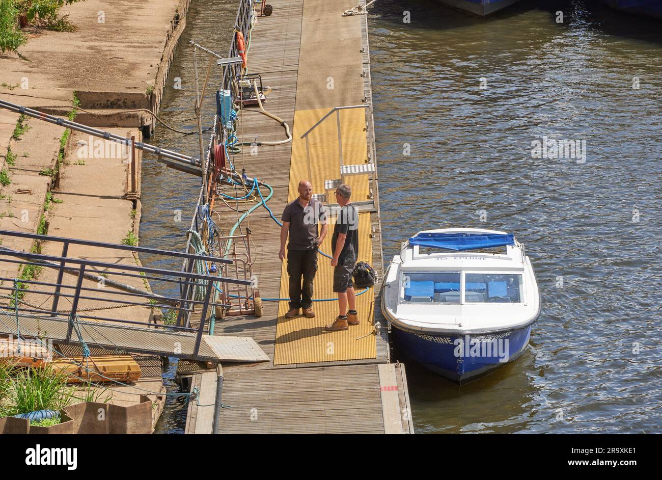 Two men in conversation next to a river boat Stock Photo - Alamy